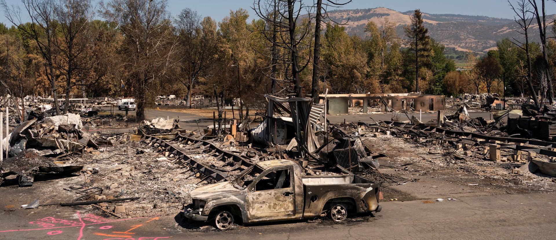A burned tuck sits in front of burned homes in a mobile home park that ...